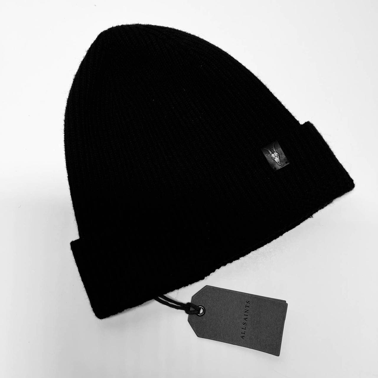 A leather brand tab marks a classic beanie knit from... - Depop