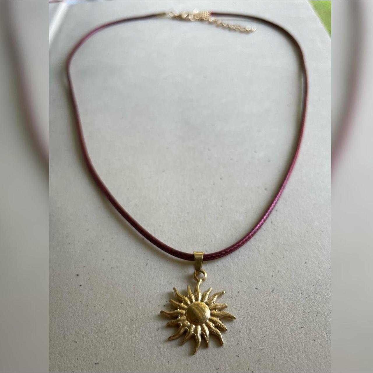 Gold sun cord necklace! Displayed on a burgundy red... | Depop