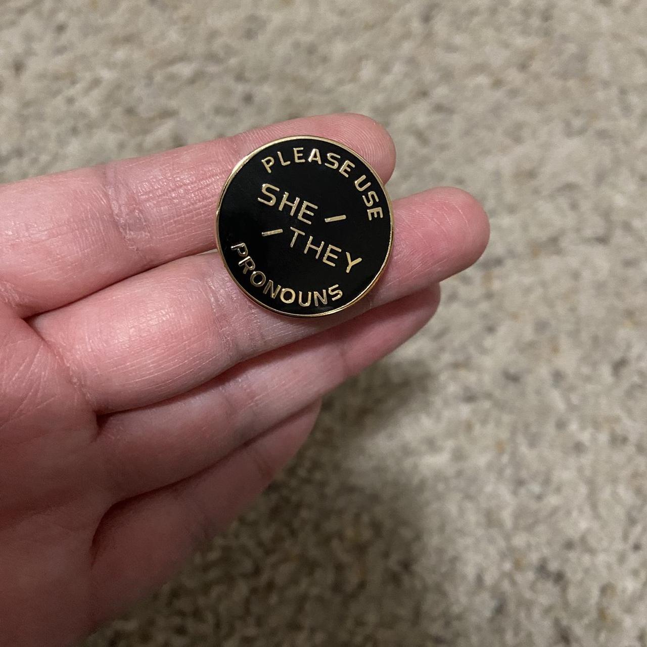 She/They black & gold pronoun enamel pin from Gamut... - Depop