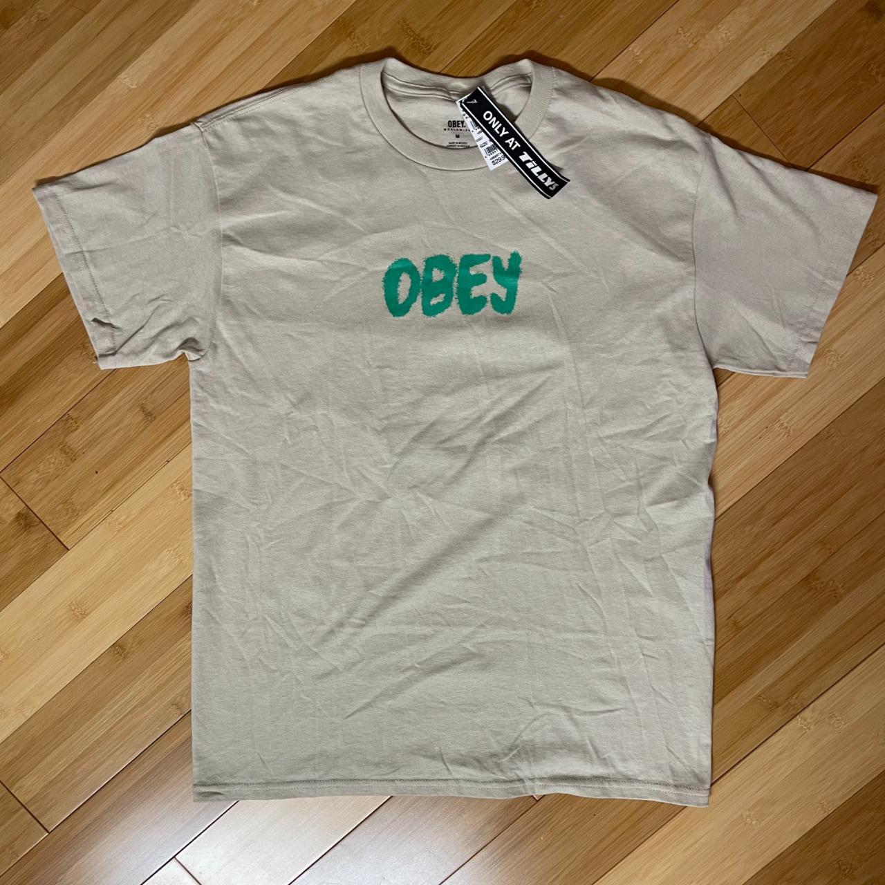 beige Obey green spray paint tee medium... - Depop