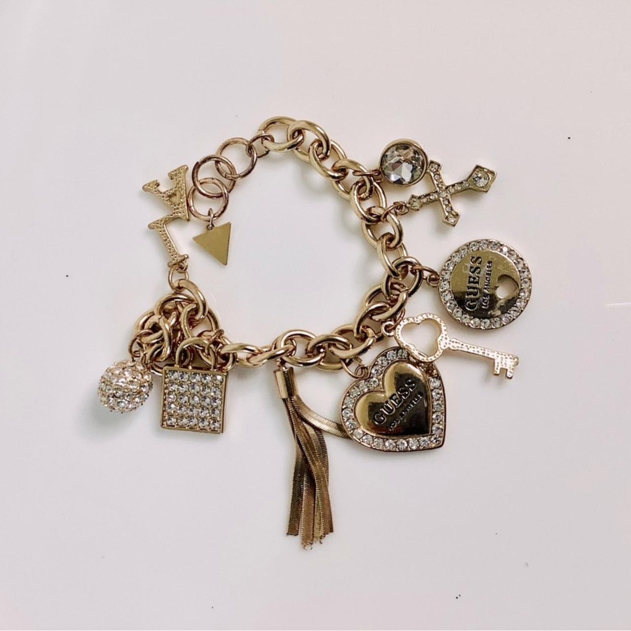 Heavy gold tone charm link bracelet by Guess in good... - Depop